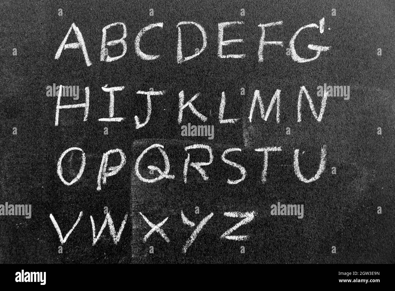 White color chalk hand drawing in english capital letter shape on black ...