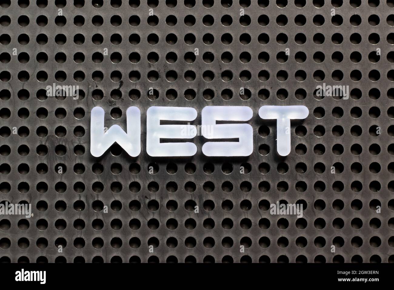 White color letter in word west on black pegboard background Stock ...