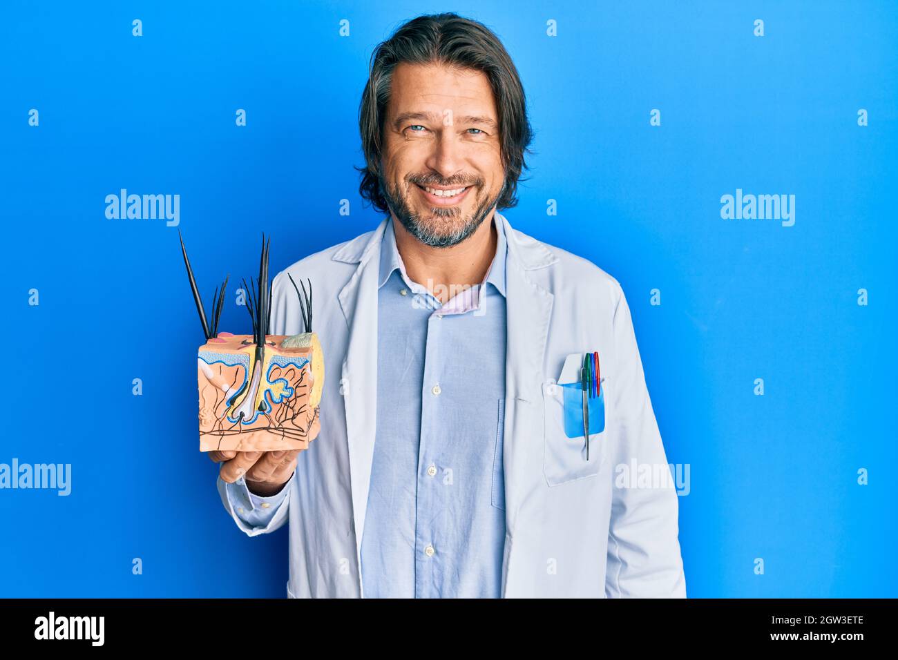 Middle age handsome doctor man holding model of human anatomical skin ...