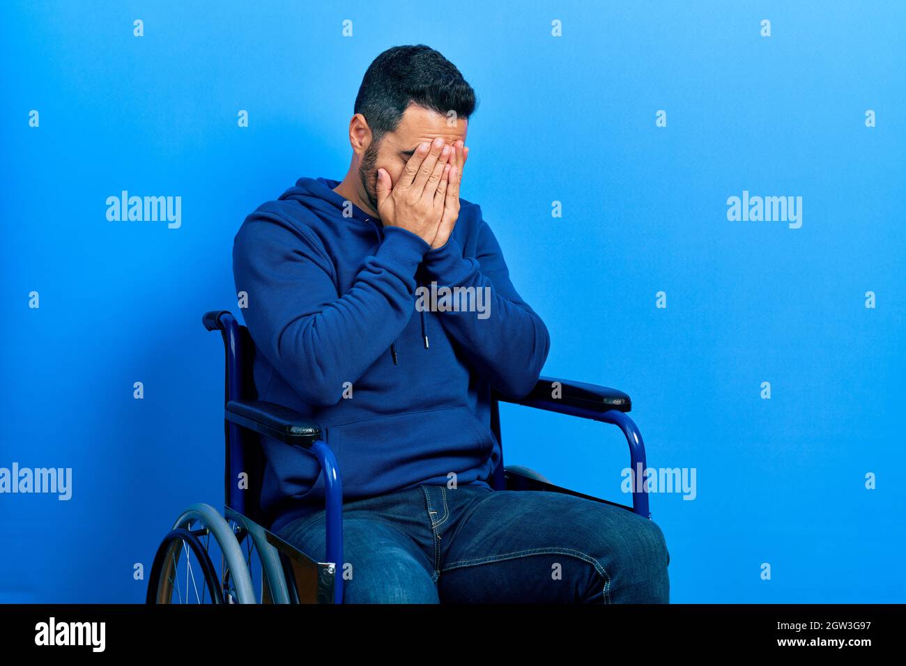 Handsome hispanic man with beard sitting on wheelchair with sad ...