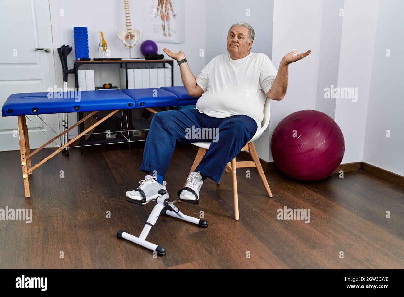 Senior caucasian man at physiotherapy clinic using pedal exerciser ...
