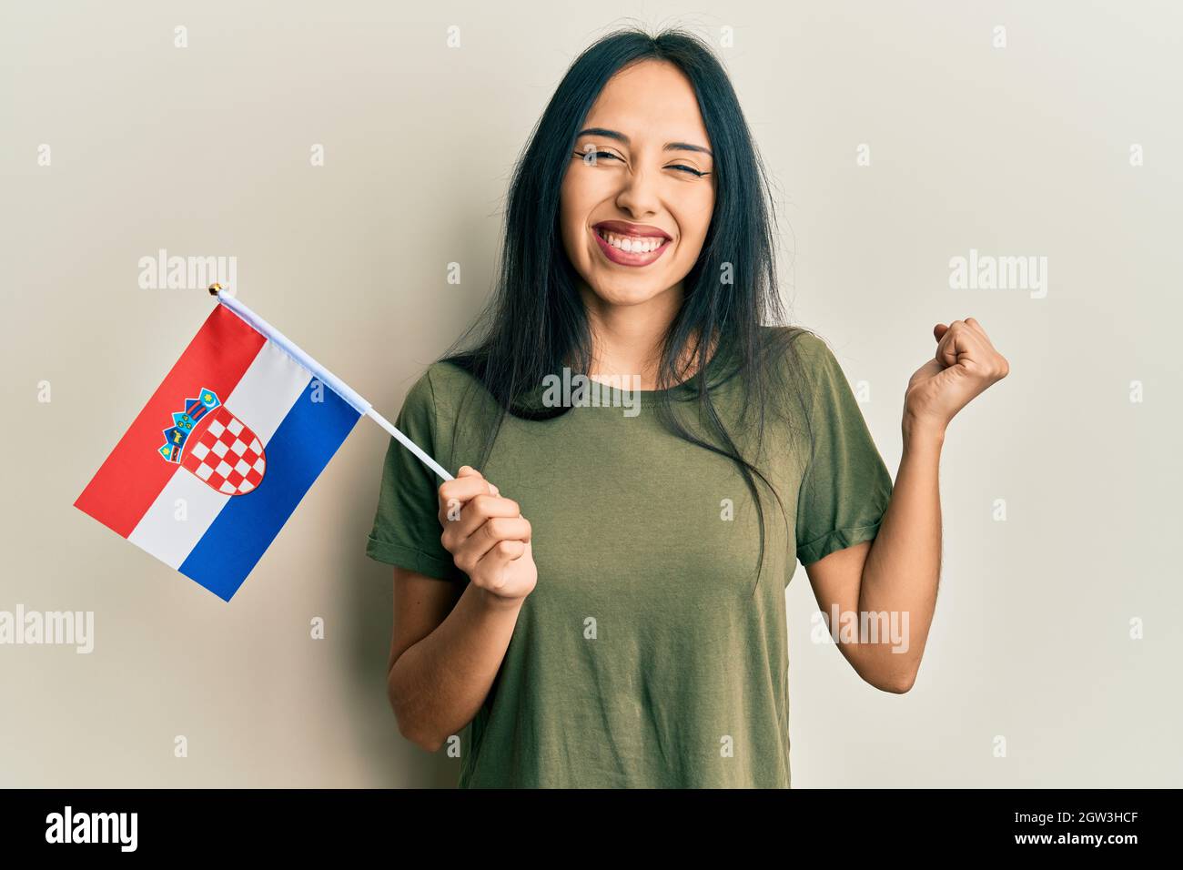 Young hispanic girl holding croatia flag screaming proud, celebrating ...