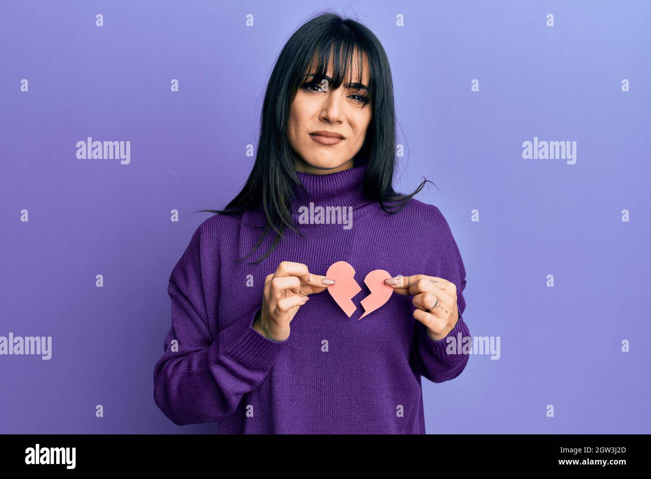 Young brunette woman with bangs holding broken heart paper shape ...