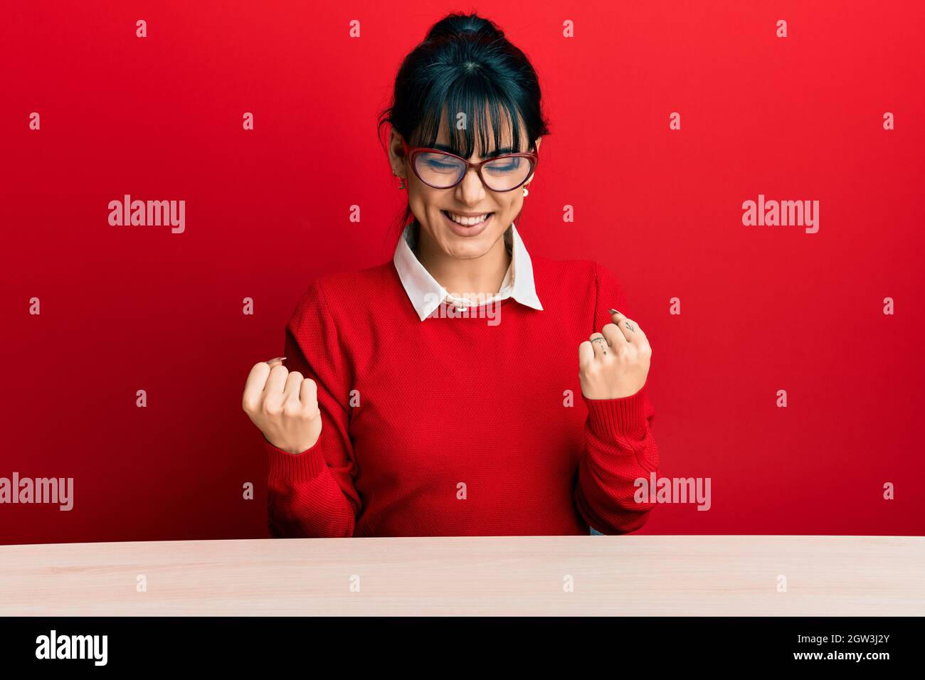 Young brunette woman with bangs wearing glasses sitting on the table ...
