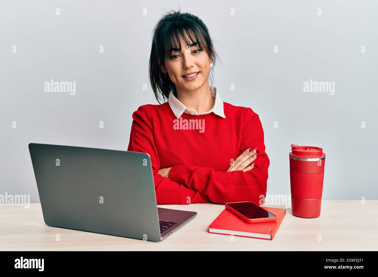 Young brunette woman with bangs working at the office with laptop happy ...