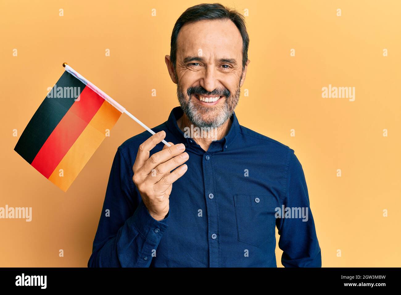 Middle age hispanic man holding germany flag looking positive and happy ...