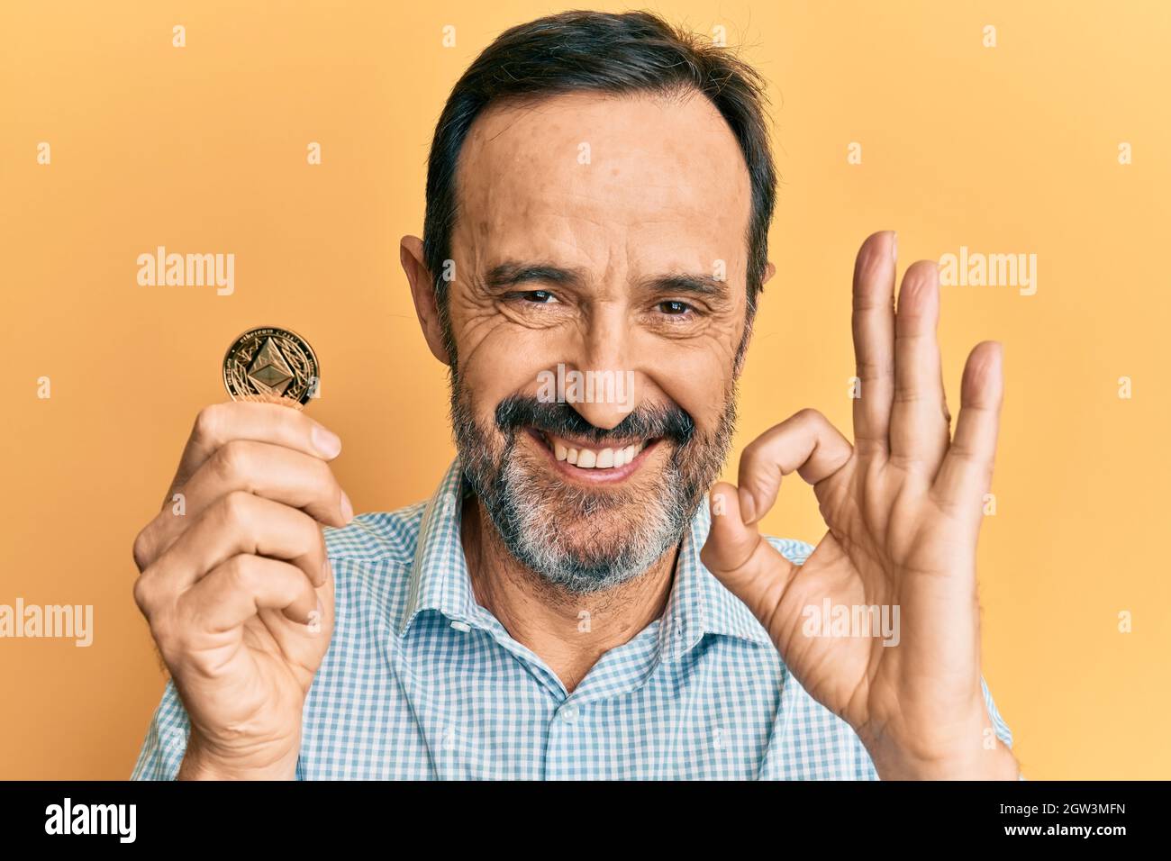 Middle age hispanic man holding virtual currency ethereum coin doing ok ...