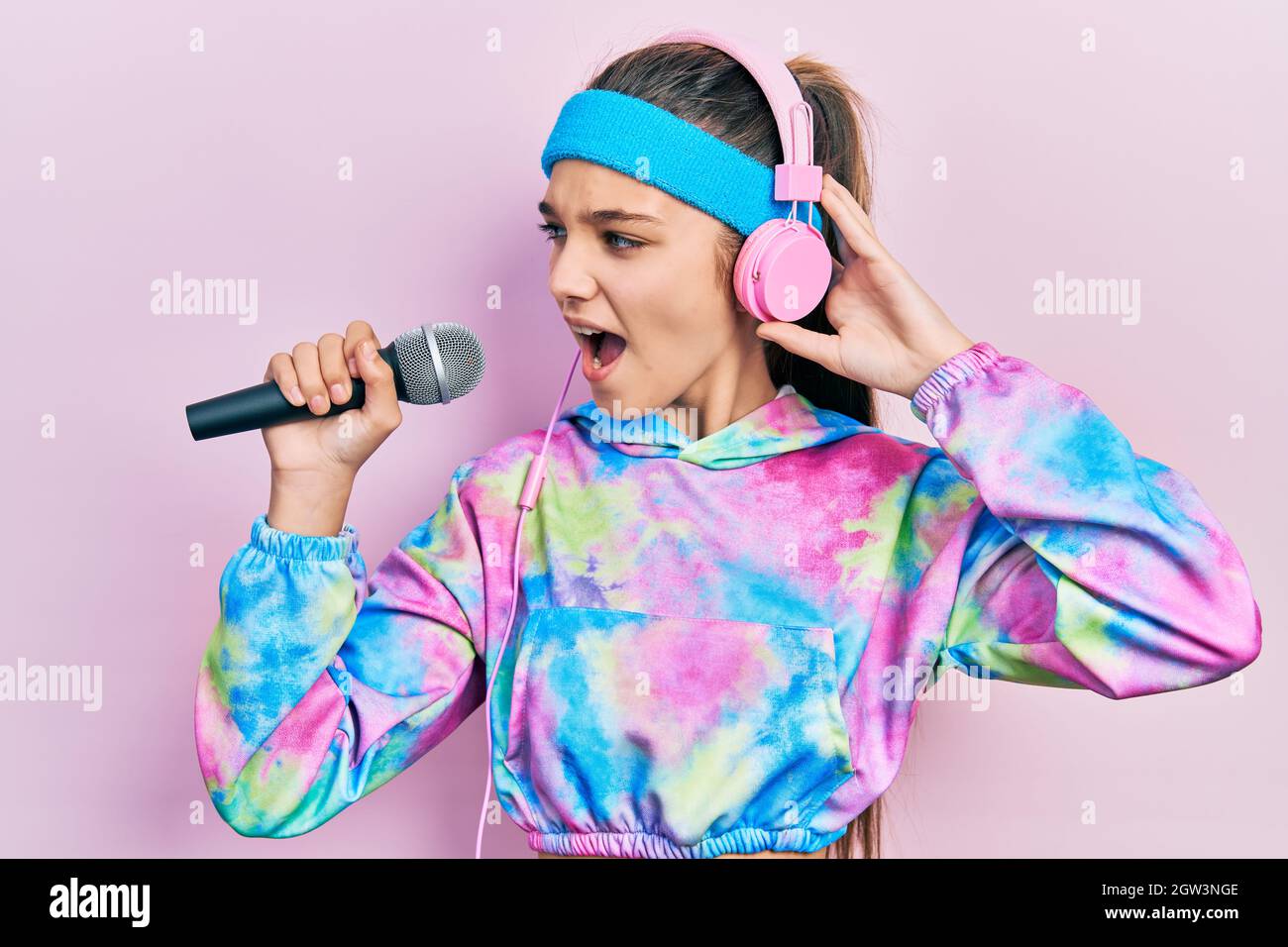 Young brunette girl singing song using microphone wearing sportswear ...