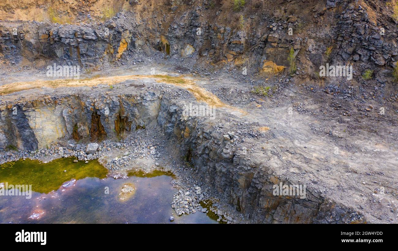 Large granite quarry with gray stone. Red water at the bottom of the ...