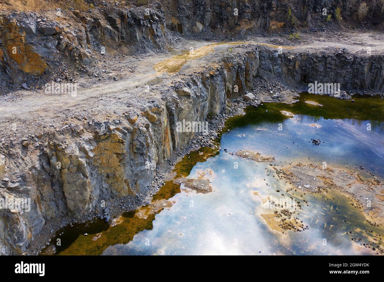 Large granite quarry with gray stone. Red water at the bottom of the ...