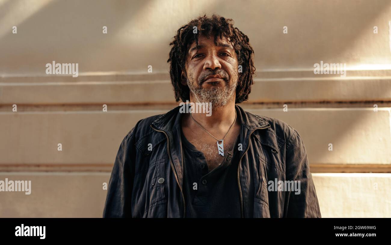 Confident homeless man looking at the camera while standing alone ...