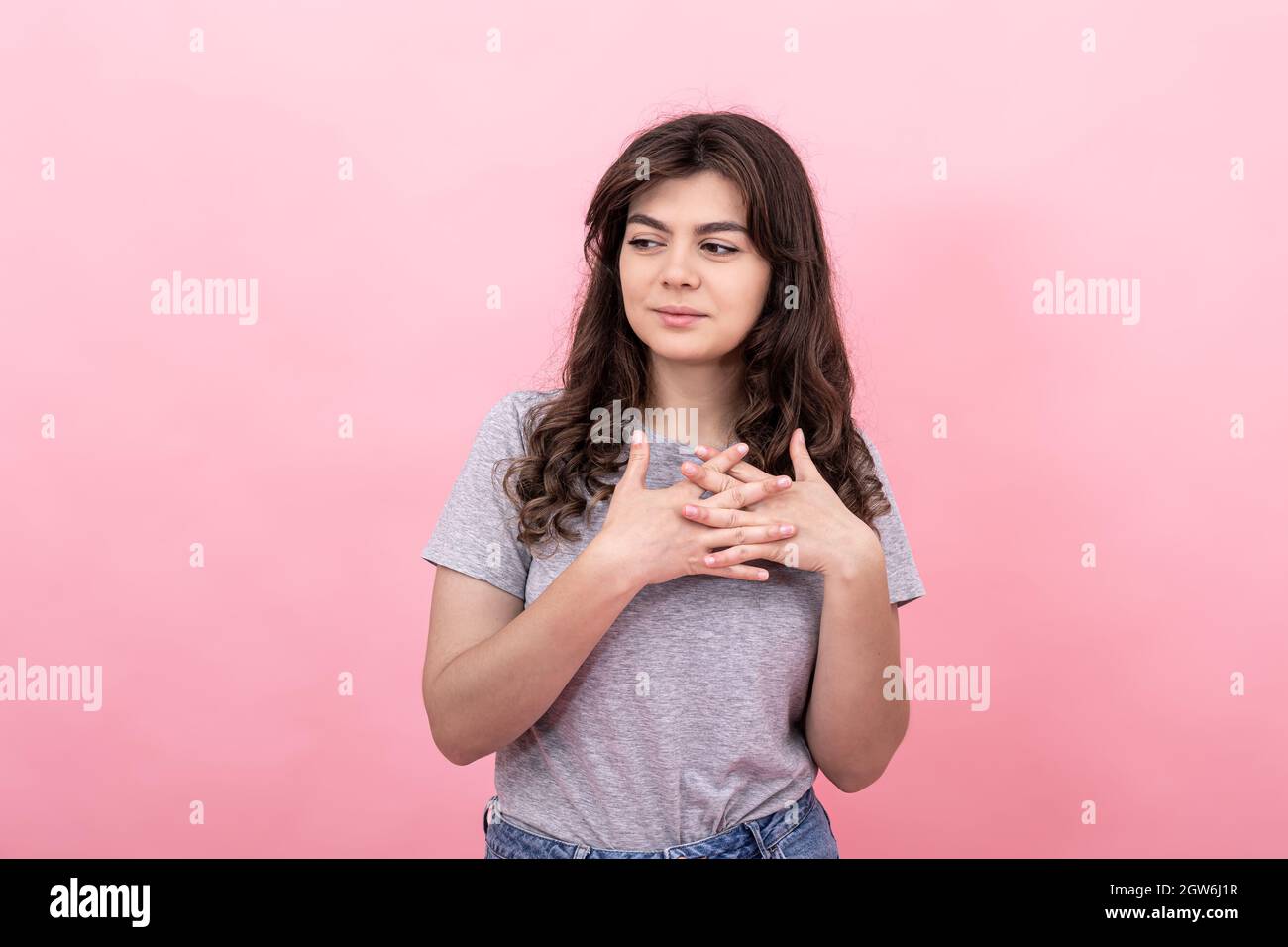Attractive modest brunette girl in casual clothes on a pink background ...