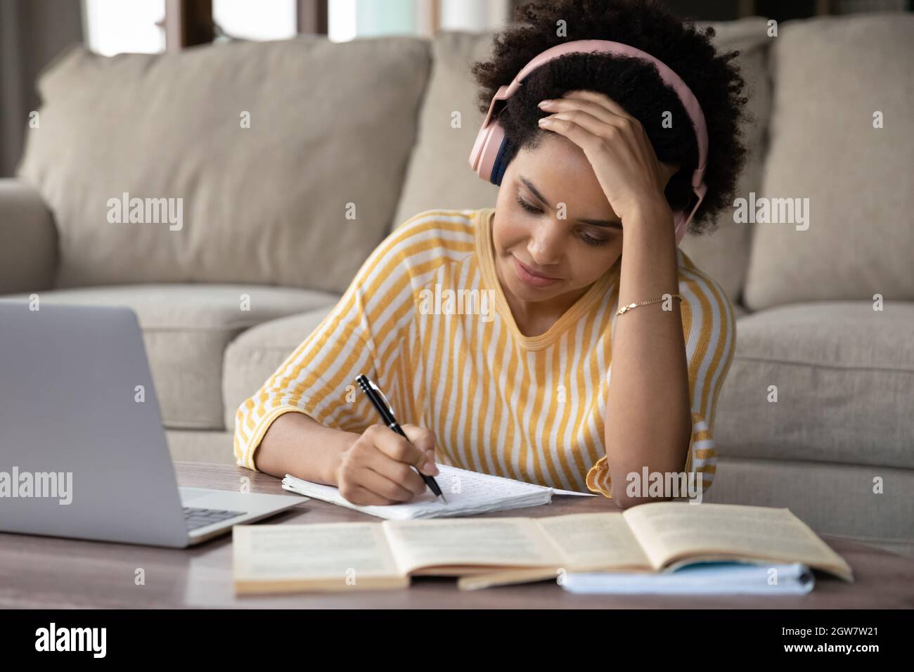 Concentrated young african american woman in headphones studying at ...