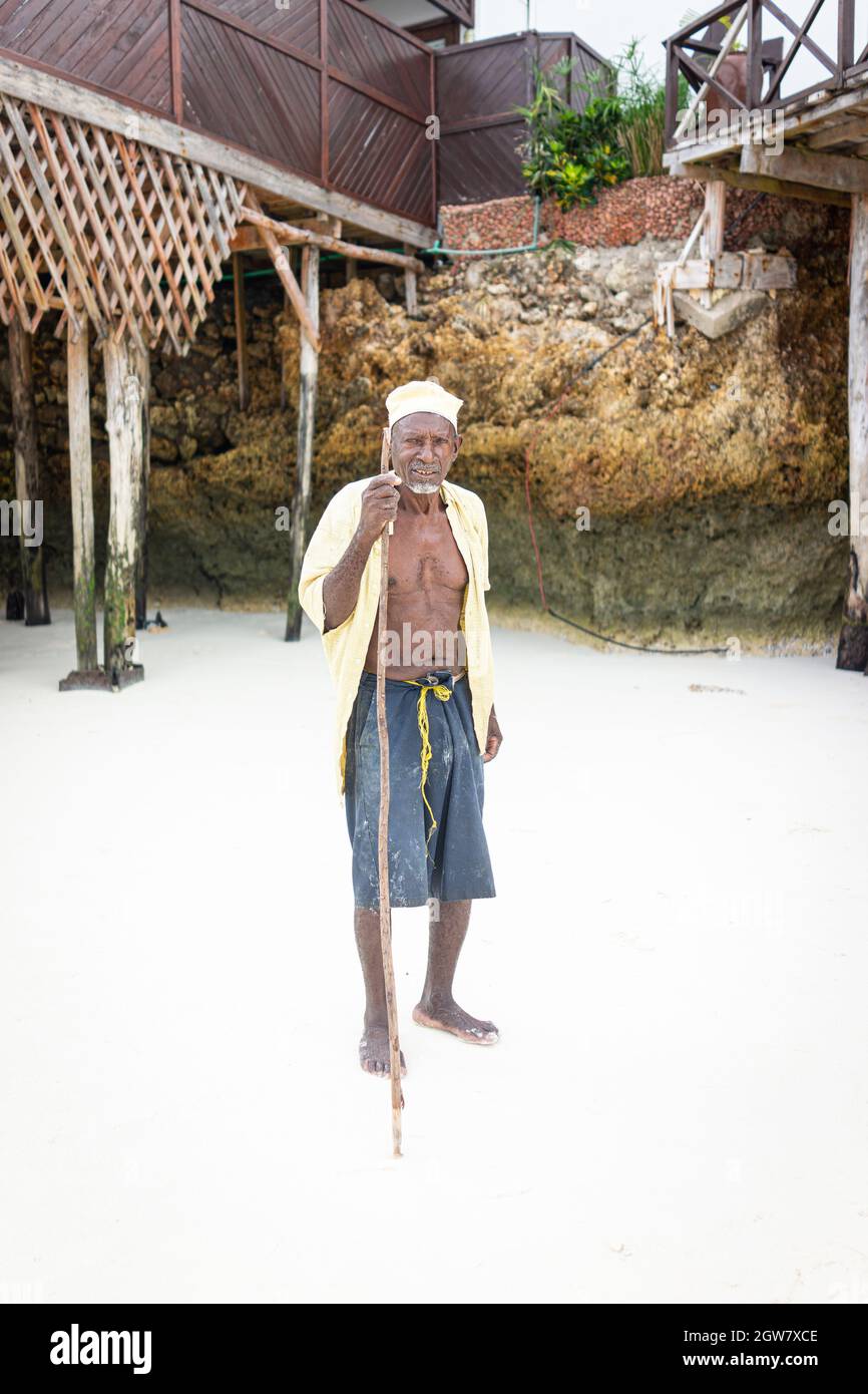 Aged African shepard walking on the beach holding stick Stock Photo - Alamy