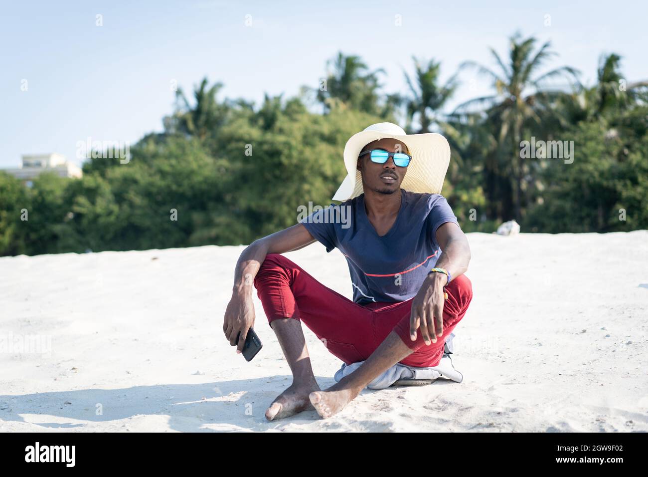 African man sitting on sandy beach Stock Photo - Alamy