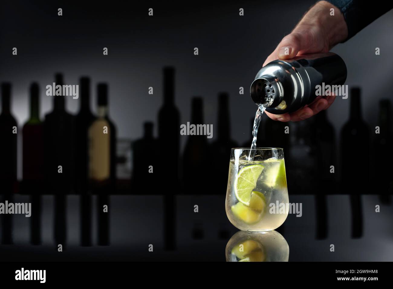 Cocktail "Caipirinha" on a black reflective background. The bartender ...