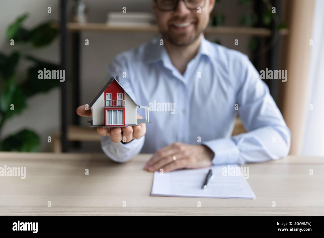 Close up smiling manager realtor consulting client, showing house model ...