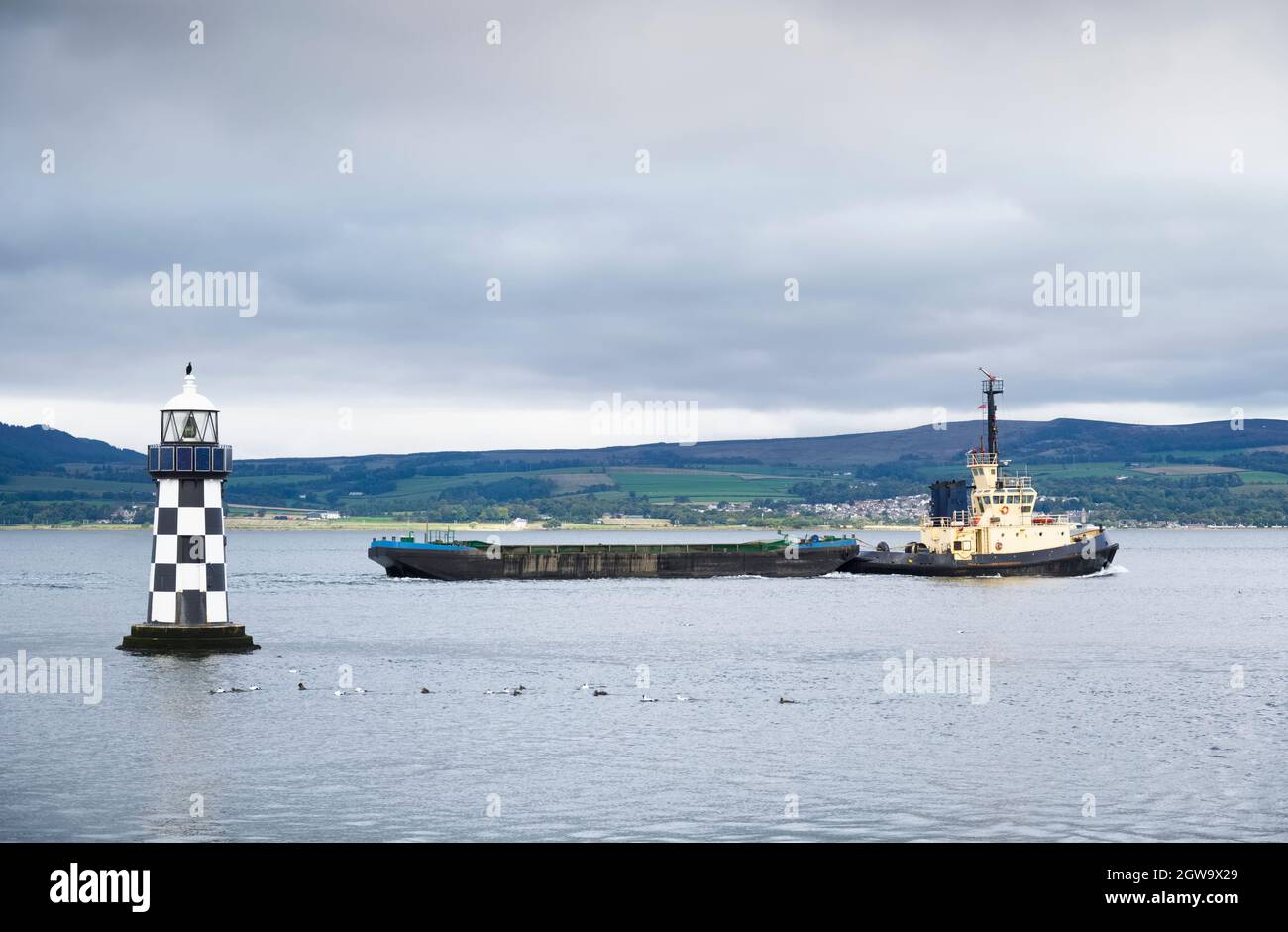Tugboat transporting floating storage container platform and lighthouse ...