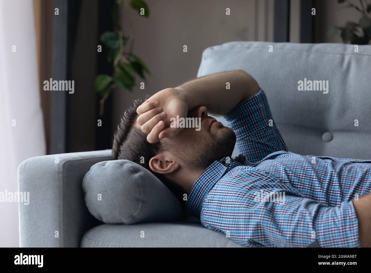 Sick man feeling headache or dizziness, lying on couch Stock Photo - Alamy