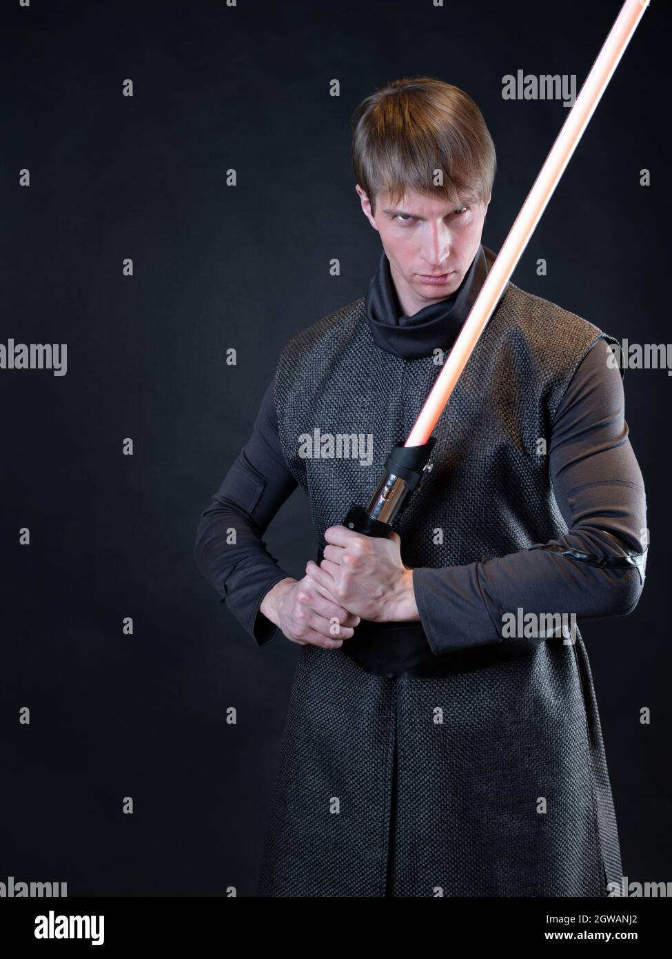 A villain with a red lightsaber, a young man in a long robe does ...