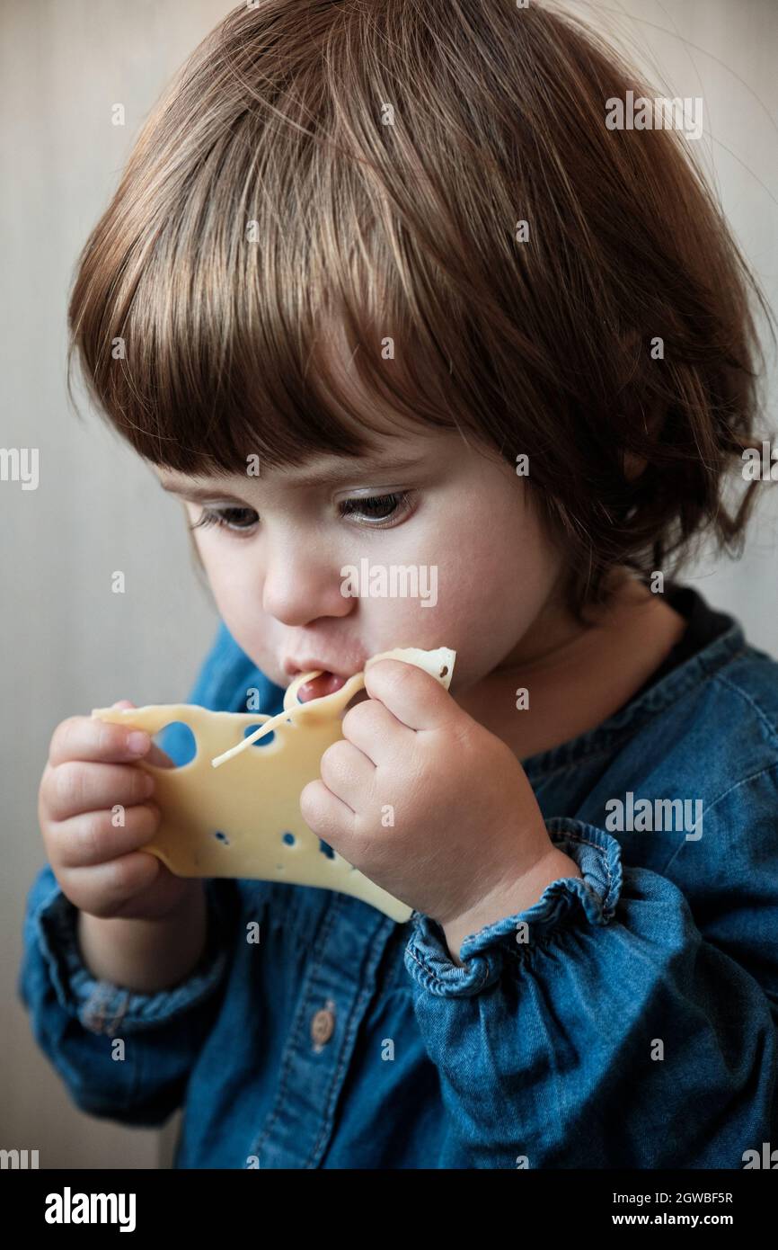 Little baby girl eating cheese. Cute baby enjoy a piece of cheese Stock ...