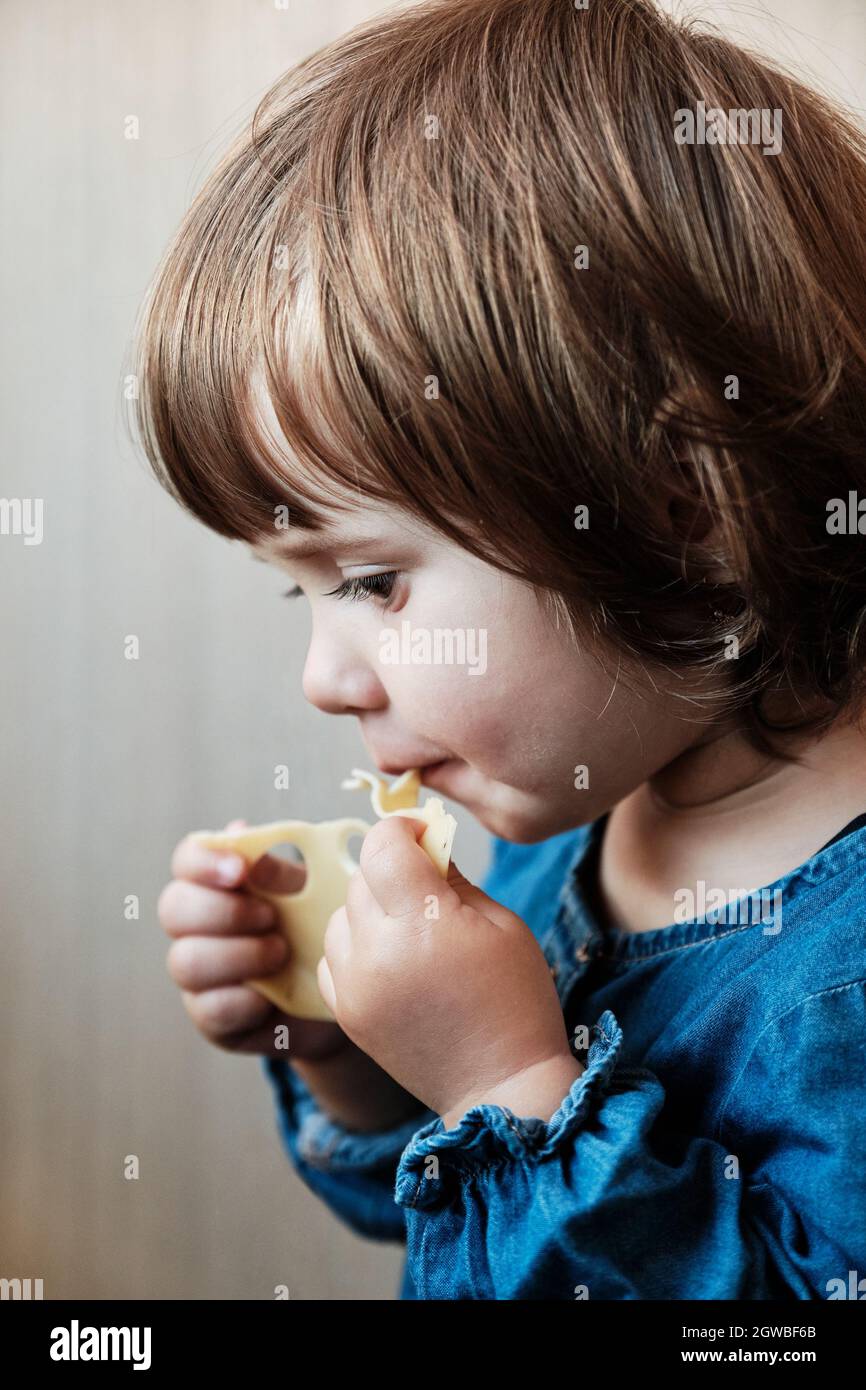 Little baby girl eating cheese. Cute baby enjoy a piece of cheese Stock ...