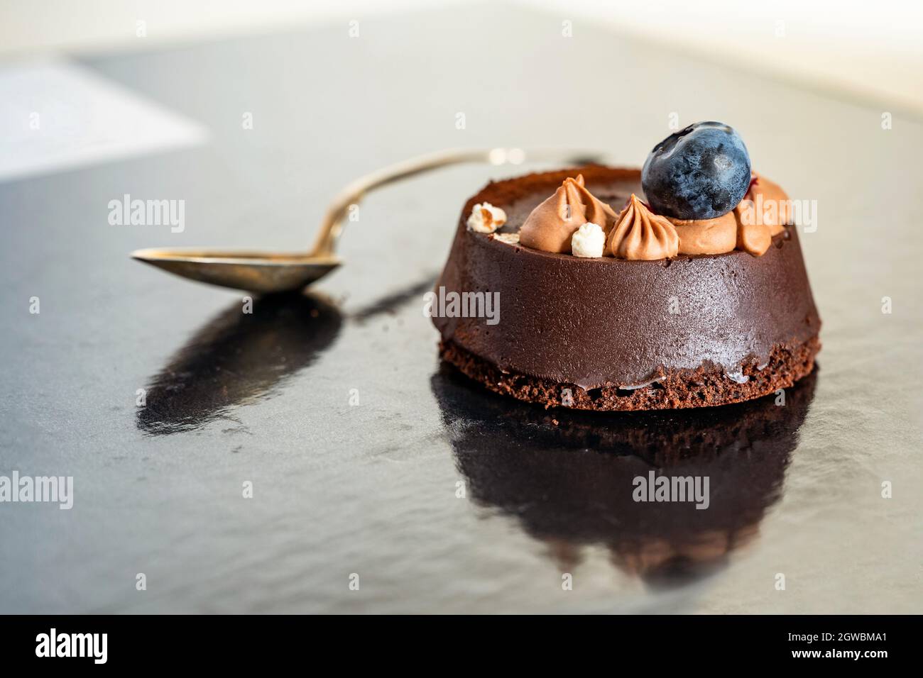 Rounded chocolate dessert (fondant) with blueberry and cream and golden ...