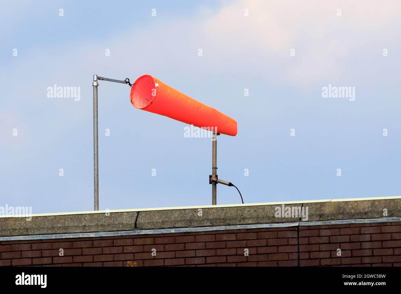 Orange windsock fixed to a metal poll on a building rooftop Stock Photo ...