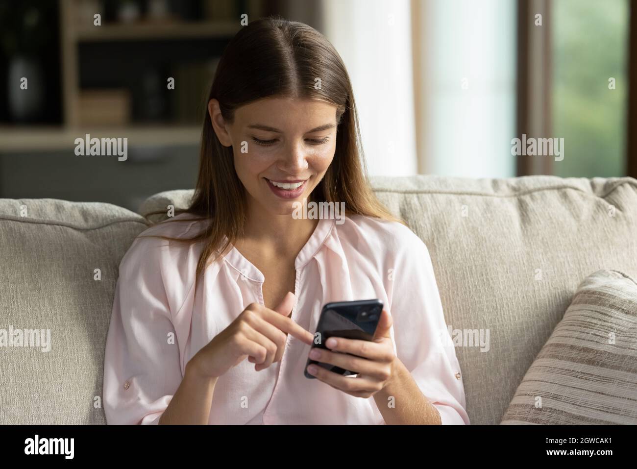 Smiling focused young woman chatting on internet on mobile phone Stock ...