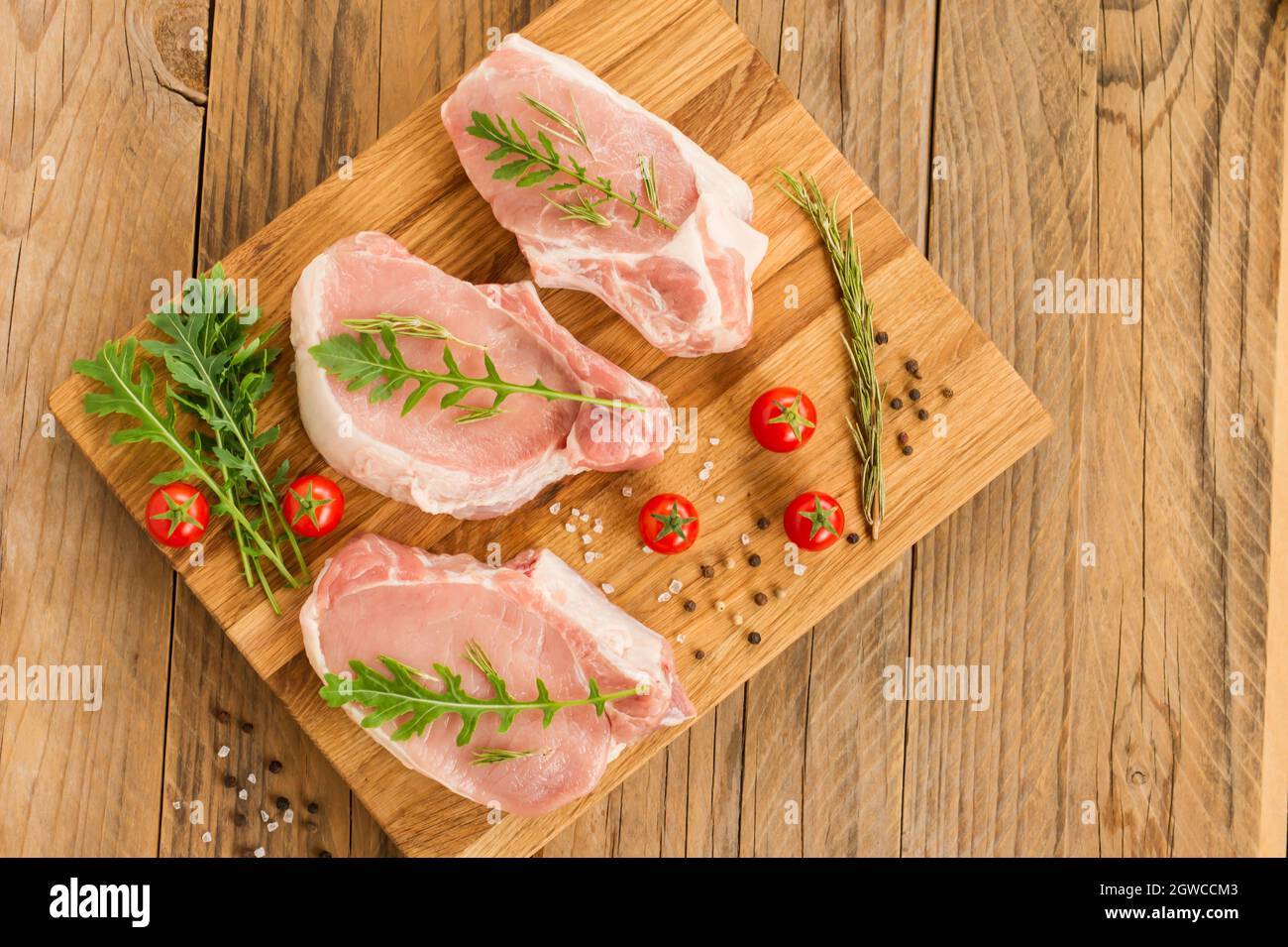 three perfect pieces of fresh pork on a cutting kitchen board with ...