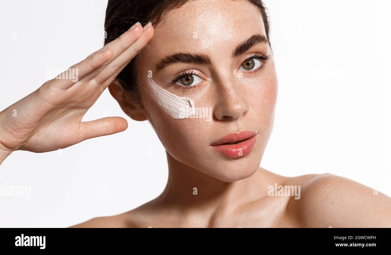 Face skin care. Woman applying cosmetic cream on clean hydrated skin ...