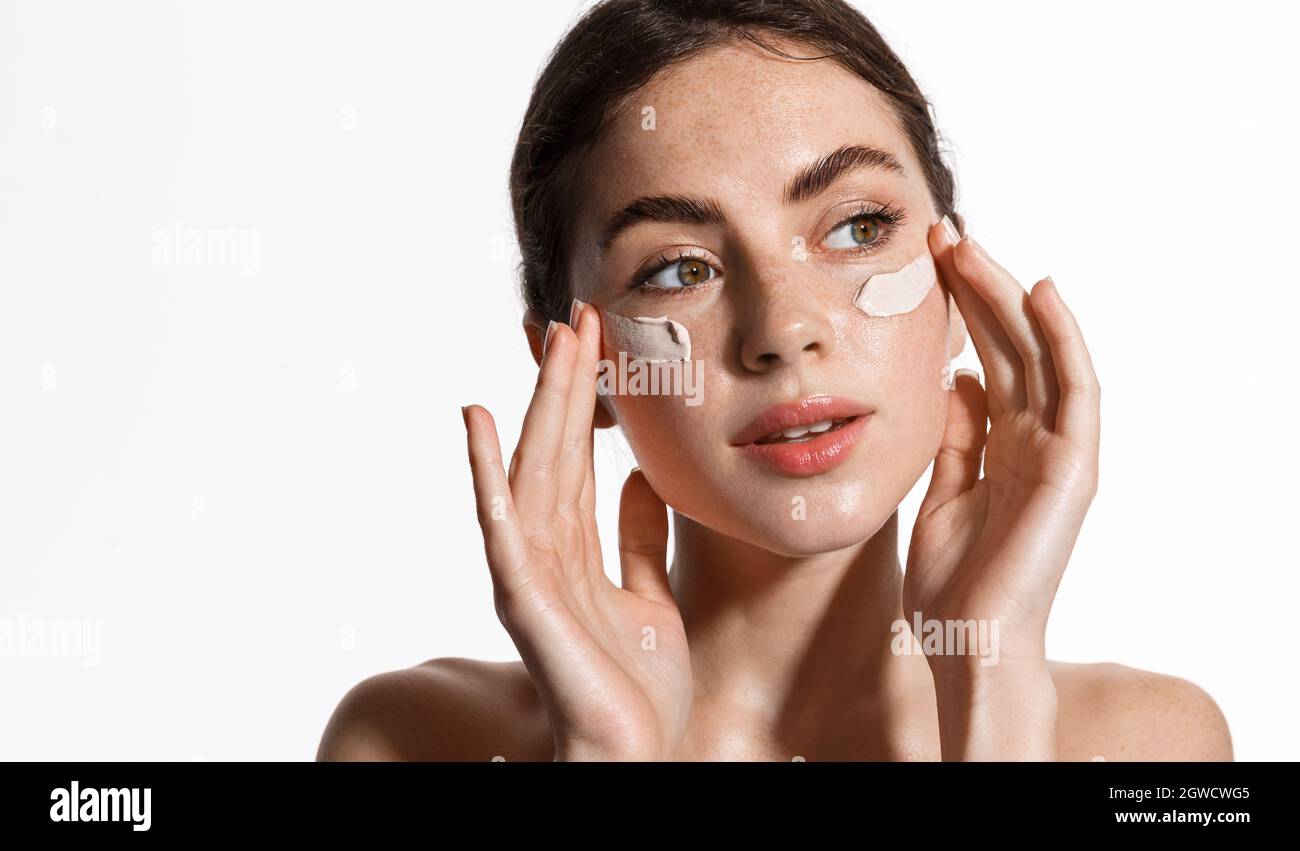 Beauty and skin care. Woman applying moisturizer, facial cream or clay ...