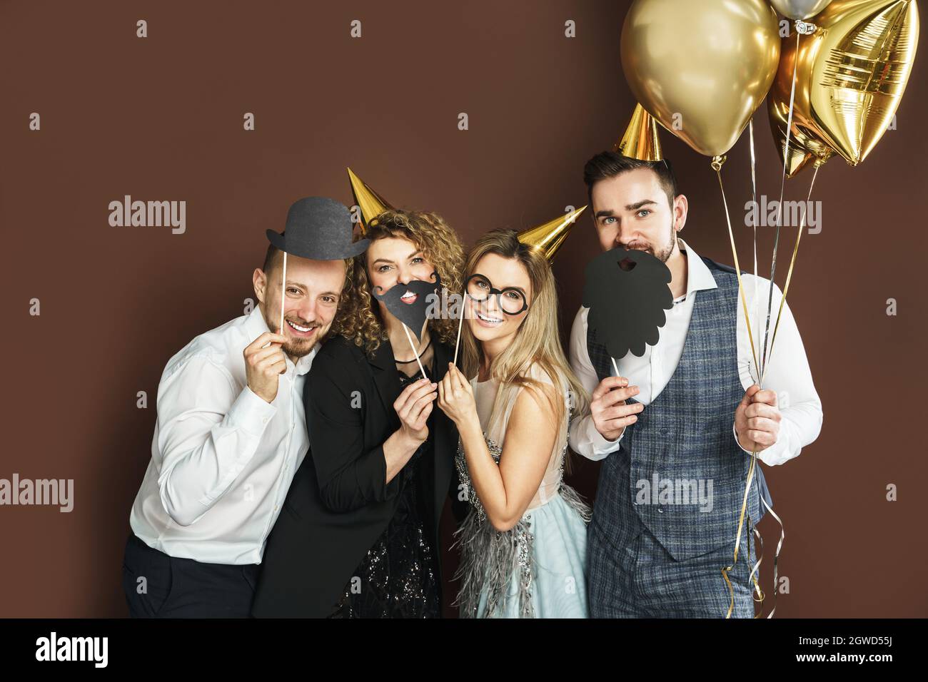 Group of happy people wearing party hats with funny photo booth props ...