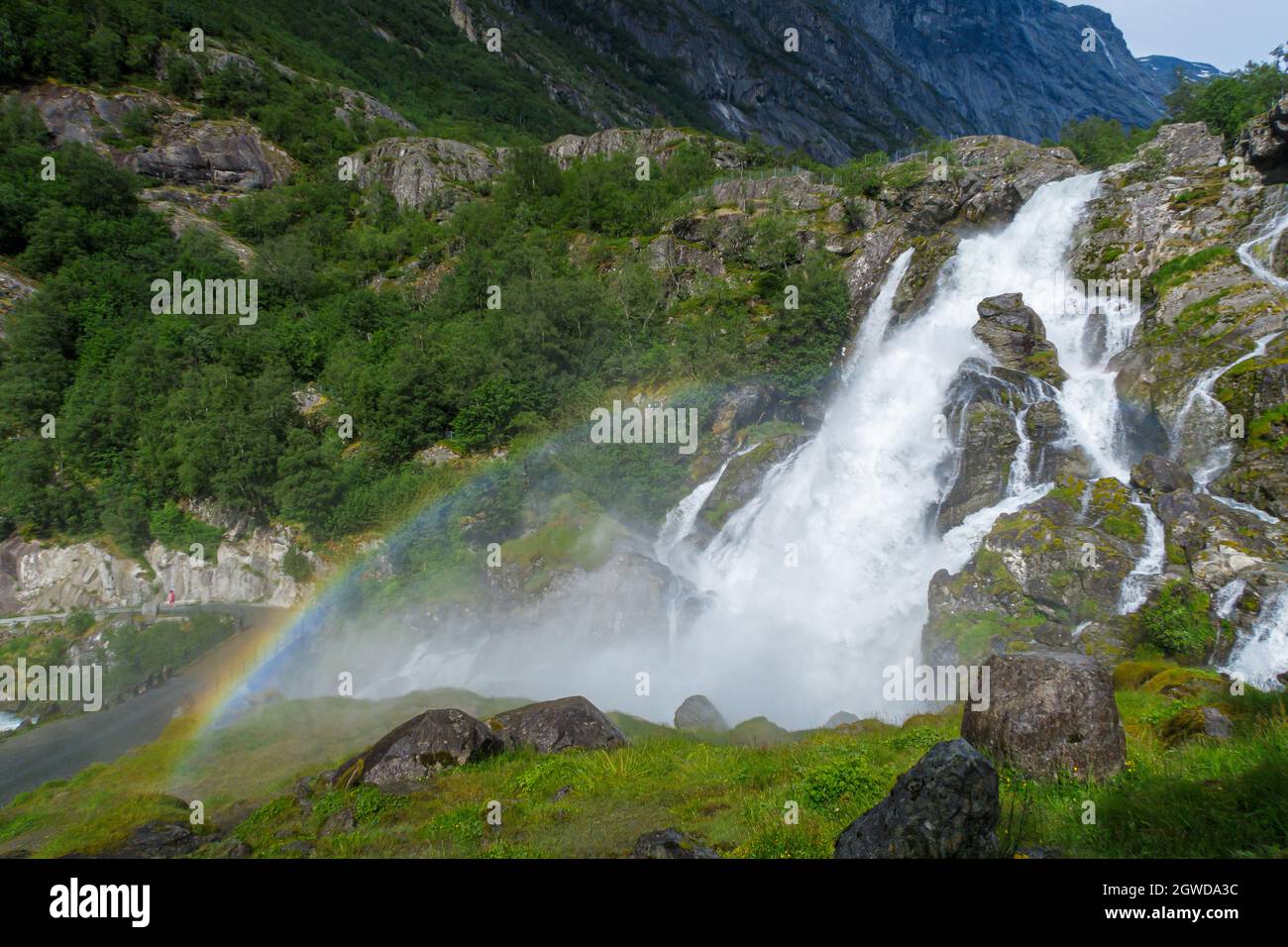 OLDEN, NORWAY- 2020 JUNE 20. Waterfall with rainbow next to the bridge ...