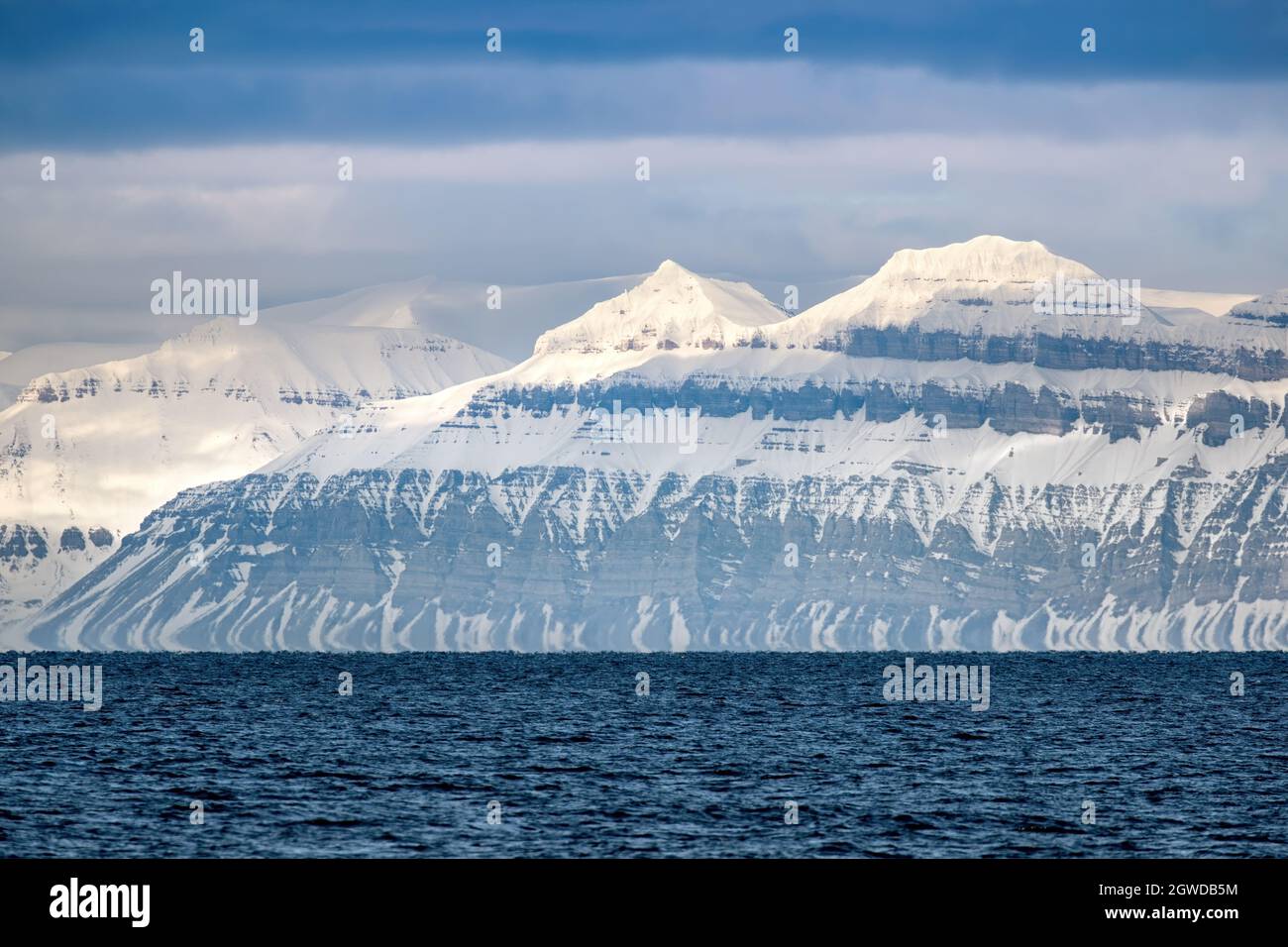 The blue water of the Nordfjorden fjord and the sunlit mountains of ...