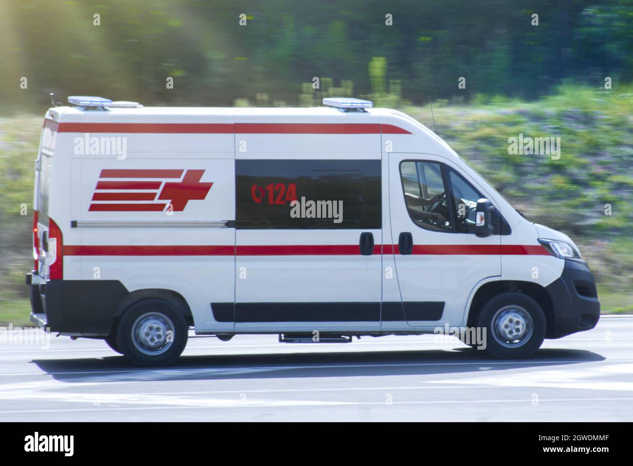 A bright summer day with a white ambulance vehicle zooming on the ...