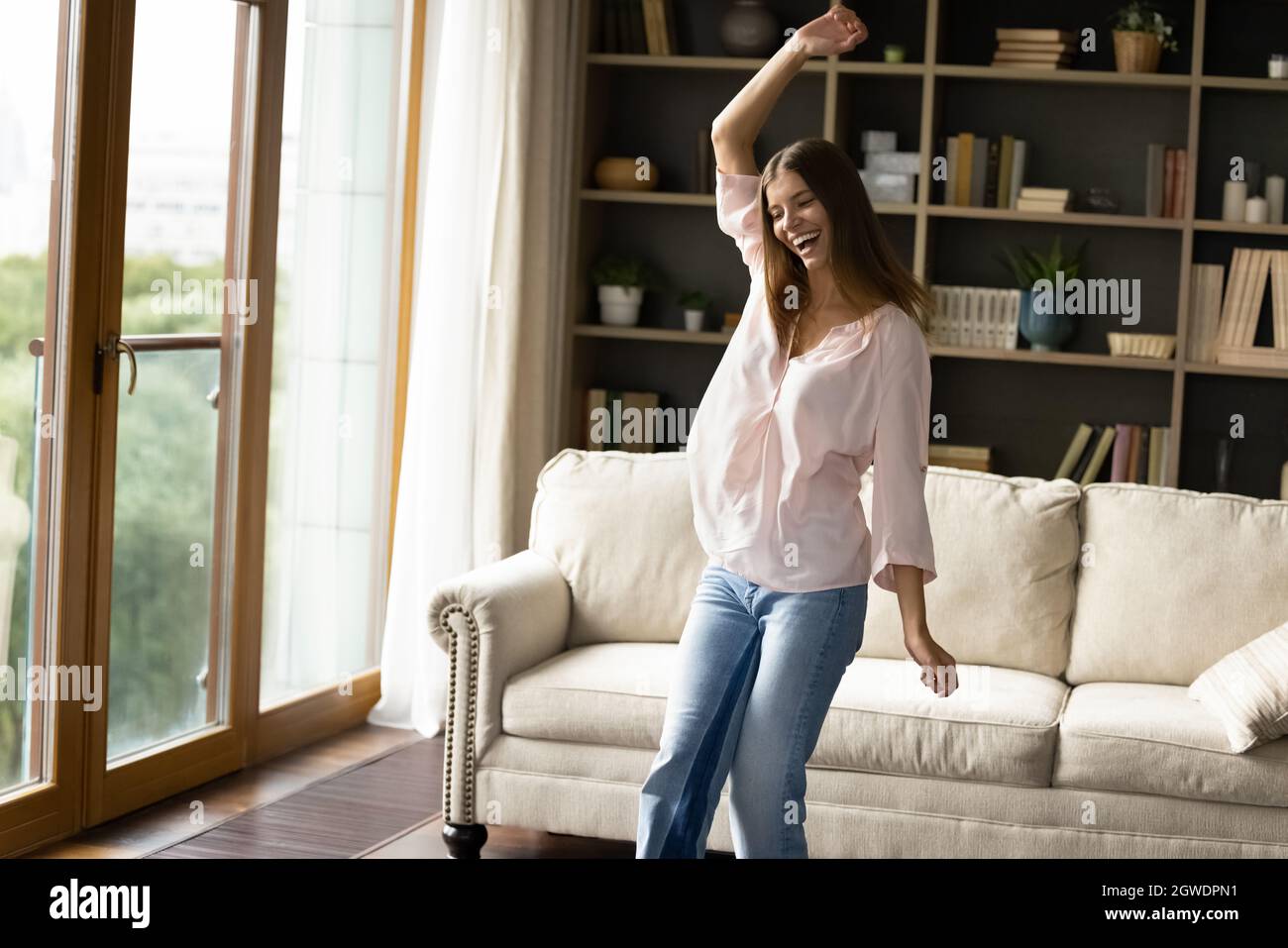 Happy excited millennial girl dancing at home, singing to music Stock ...