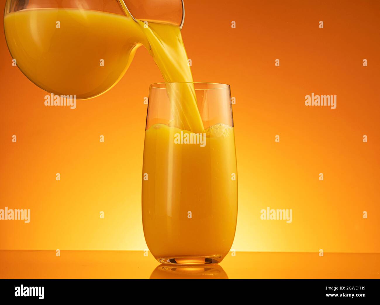 Orange juice pouring into glass with splash Stock Photo - Alamy