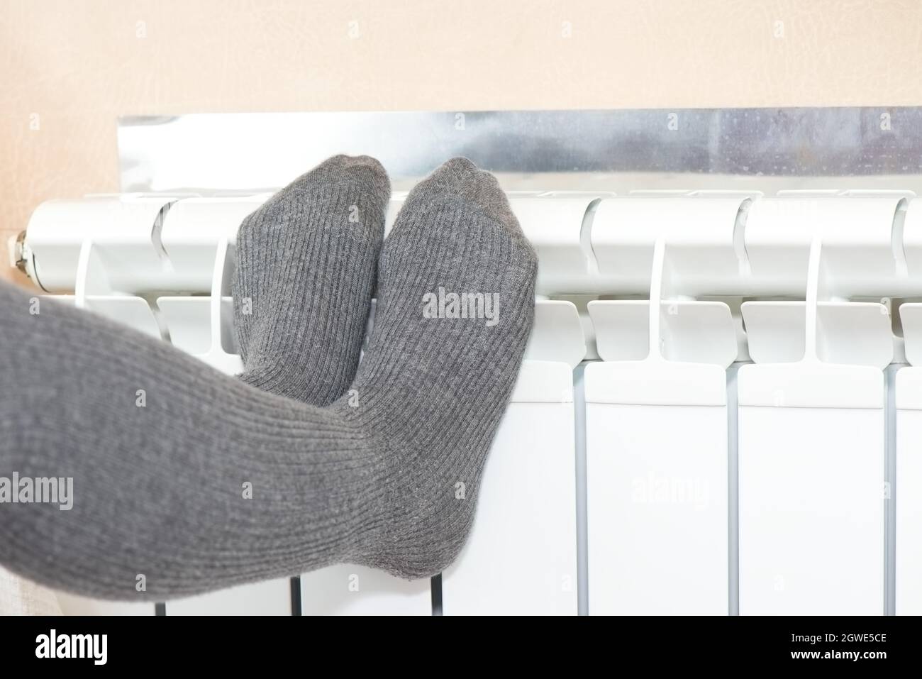 Woman warming up her feet on heater, detail Stock Photo - Alamy