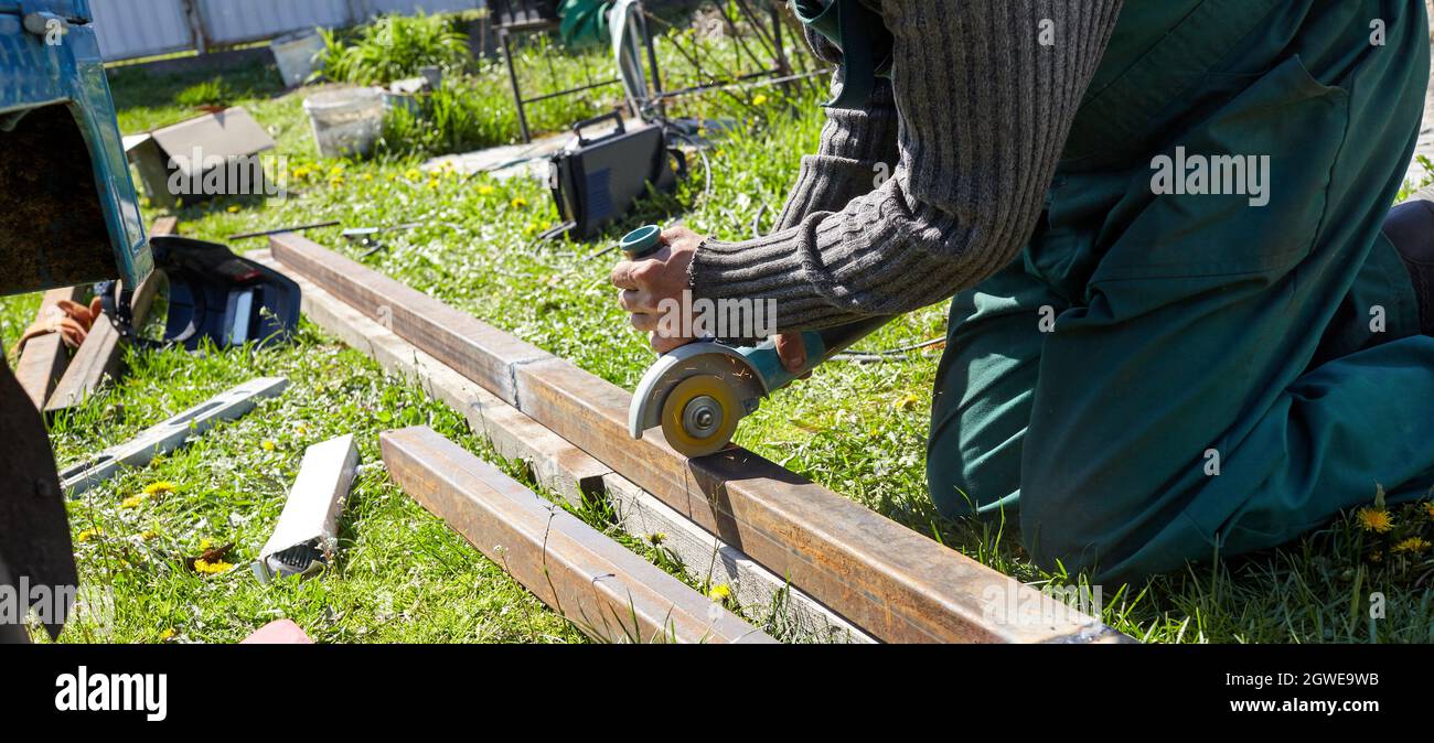 Man grinds a metal product with angle grinder outdoors. Metal ...