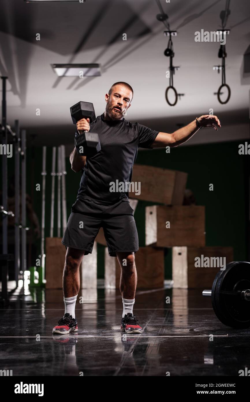 Muscular athlete lifting very heavy weights. Man working out indoors ...