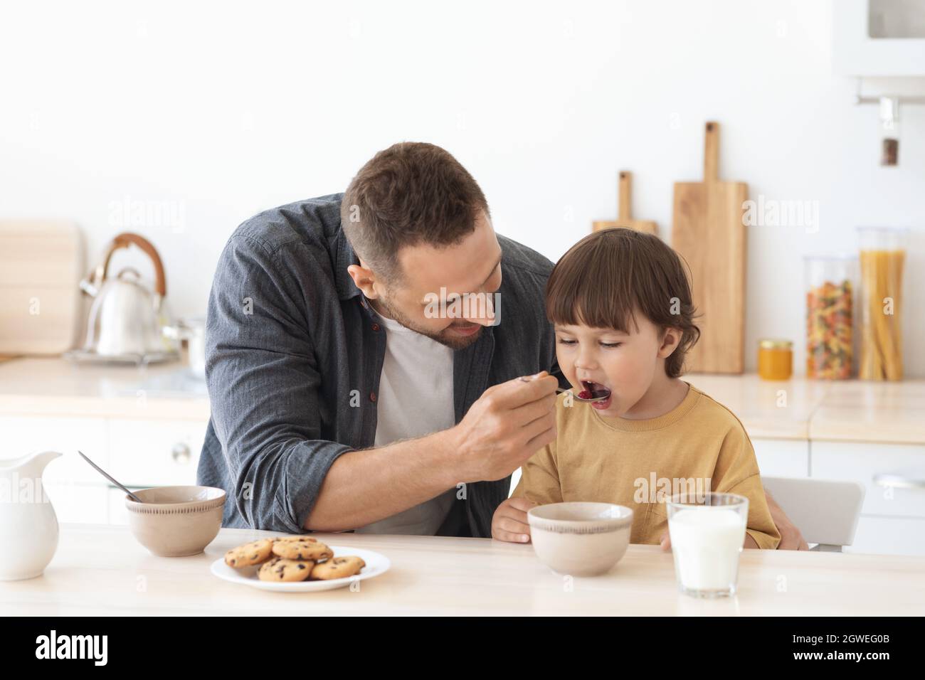 Kids nutrition. Loving daddy feeding his little son with porridge ...