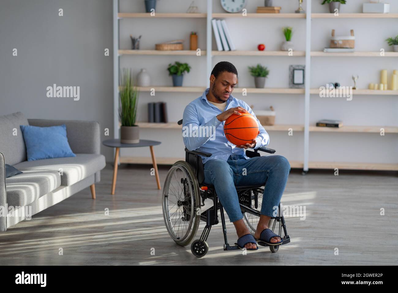 Paraplegic basketball player in wheelchair holding ball with grief ...