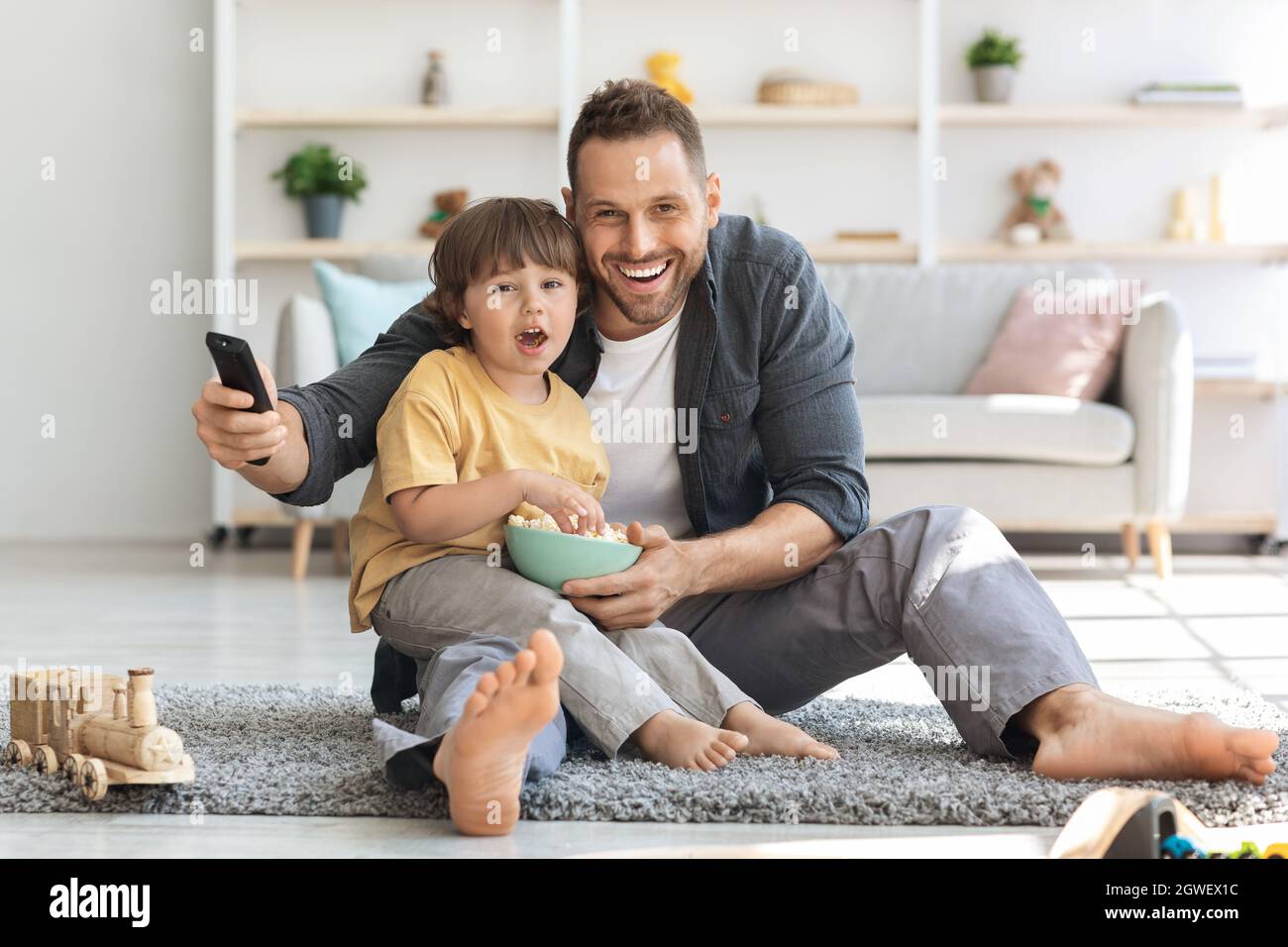 Family pastime. Emotional young father watching movies on tv with his ...