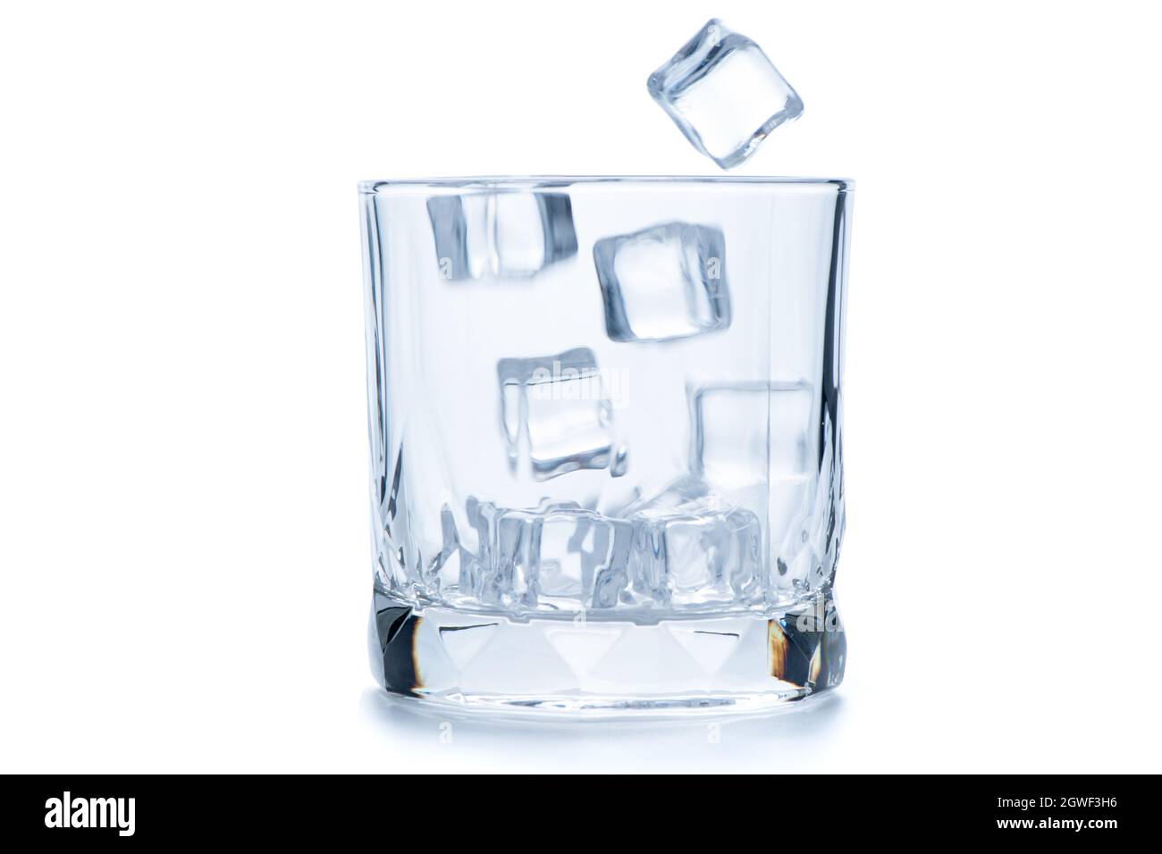 drop ice cubes in to empty Rock glass or Old Fashioned glass isolated ...