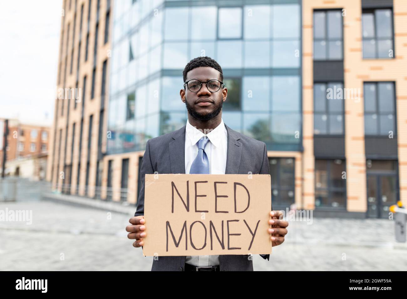 African american businessman in suit holding sign with words NEED MONEY ...