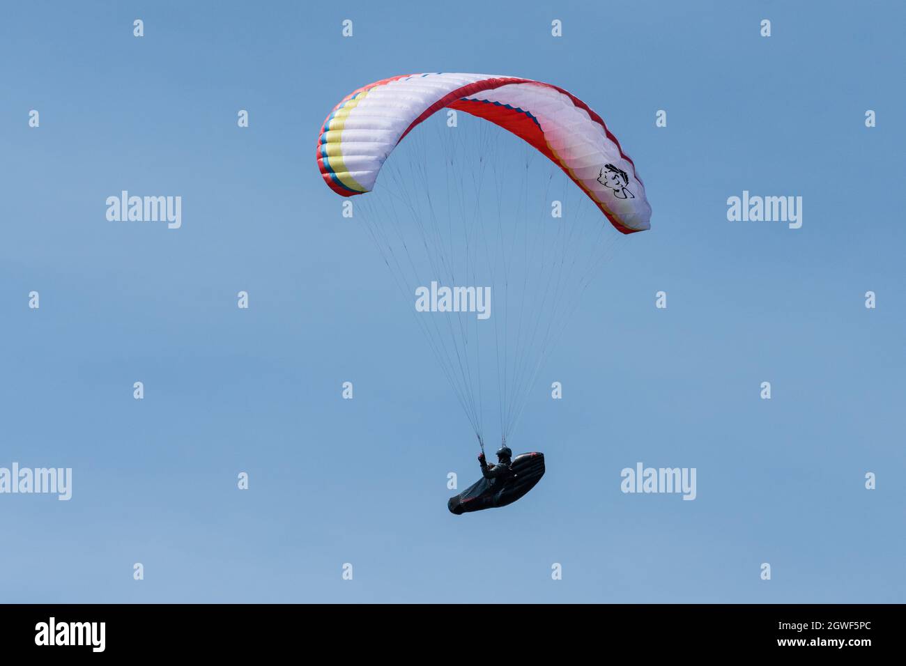 A paraglider pilot in an aerodynamic fairing harness soars after taking ...