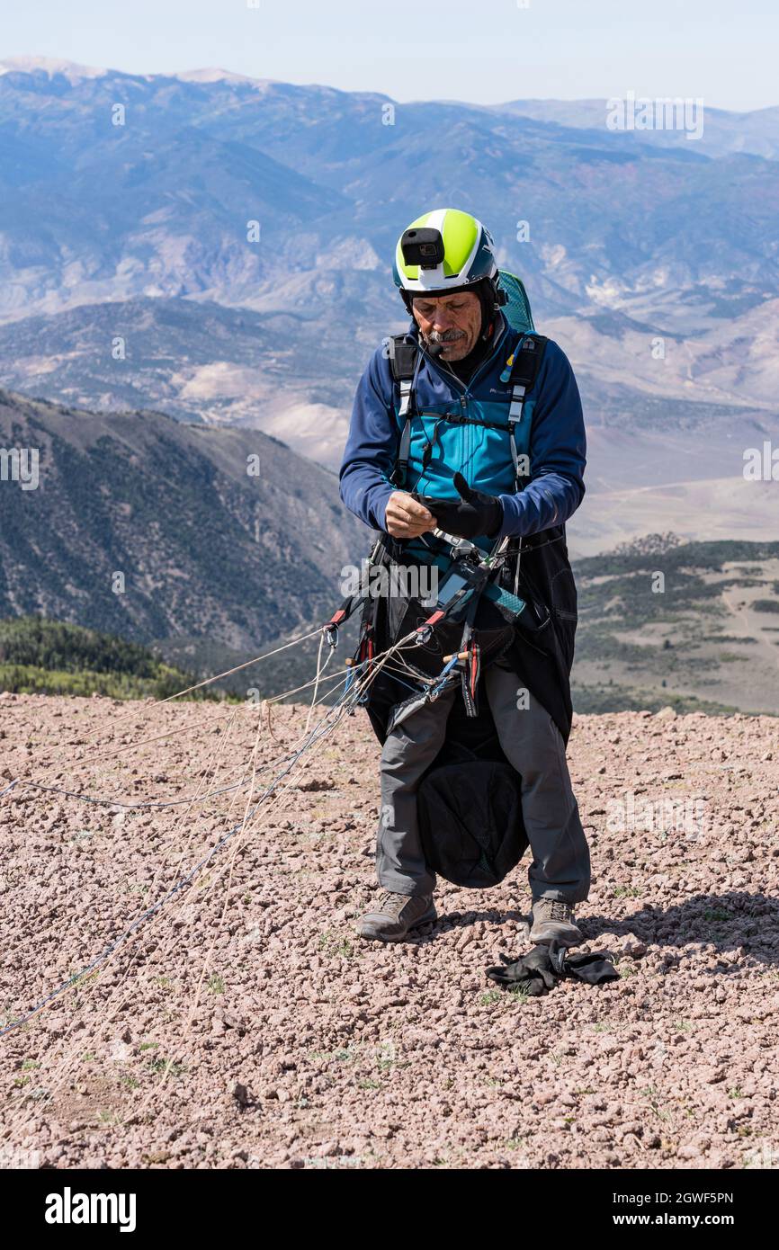 A paraglider pilot prepares to launch his paraglider off the top of ...