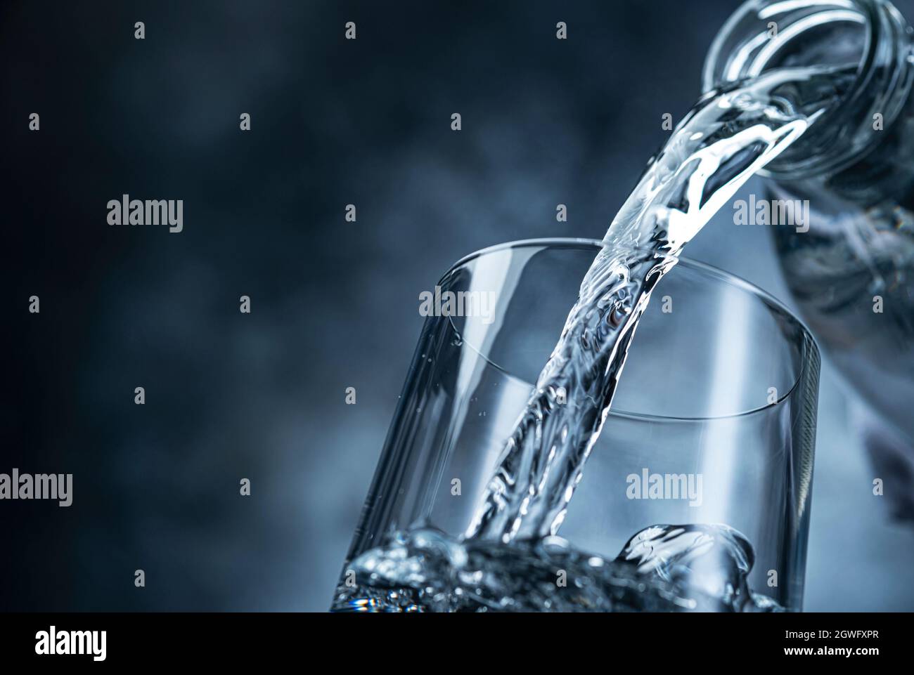Pouring water on black background Stock Photo - Alamy