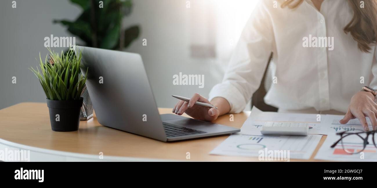 Businesswoman using calculator and laptop computer for analysis ...